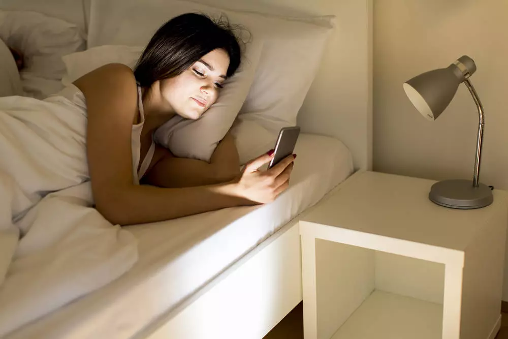 di tempat tidur dengan telefon